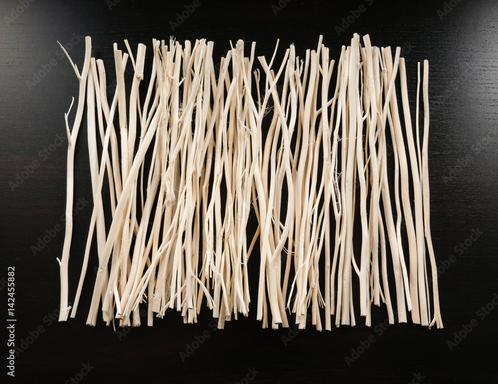 Pile of dry wooden sticks without bark scattered on dark background ...
