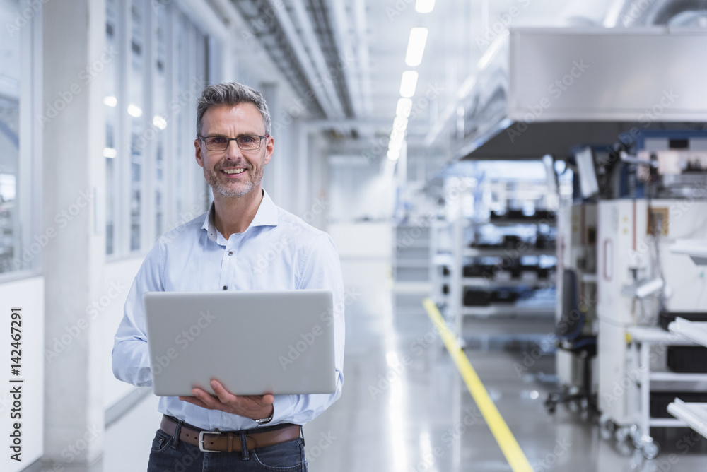 Manager on shop floor of factory using laptop Stock Photo | Adobe Stock