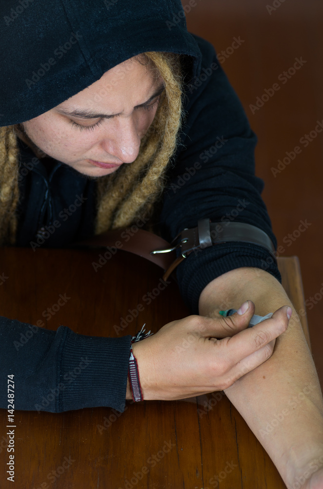 Man with drug addiction sitting down injecting narcotics into arm using ...