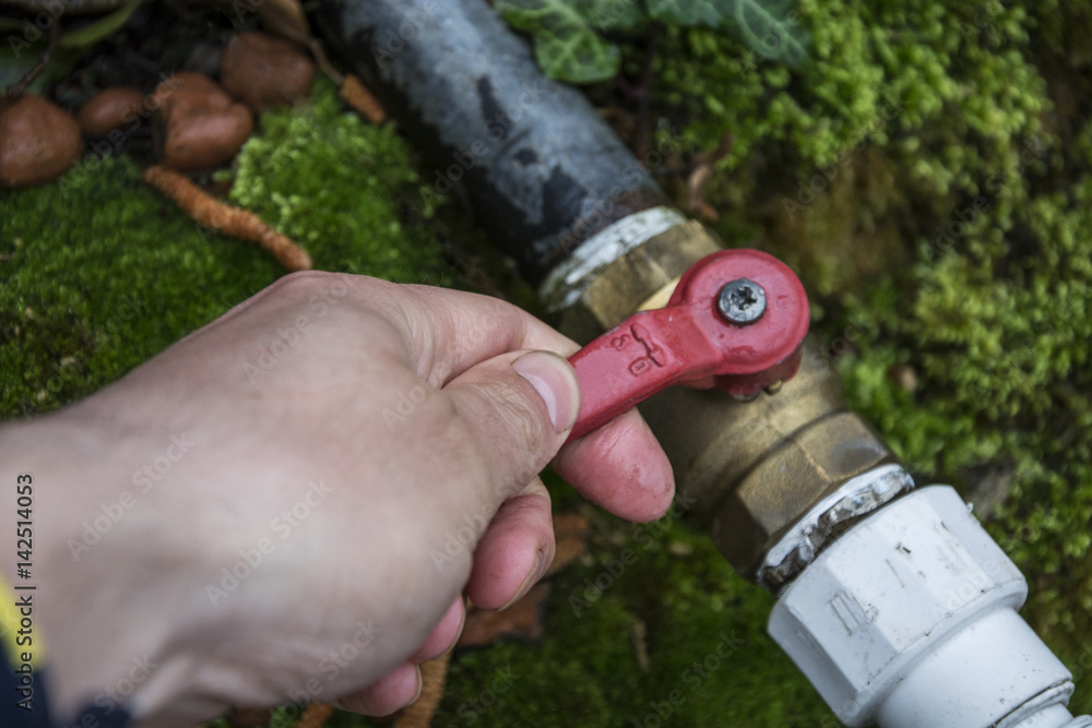 Male hand opens the tap with red handle foto de Stock | Adobe Stock