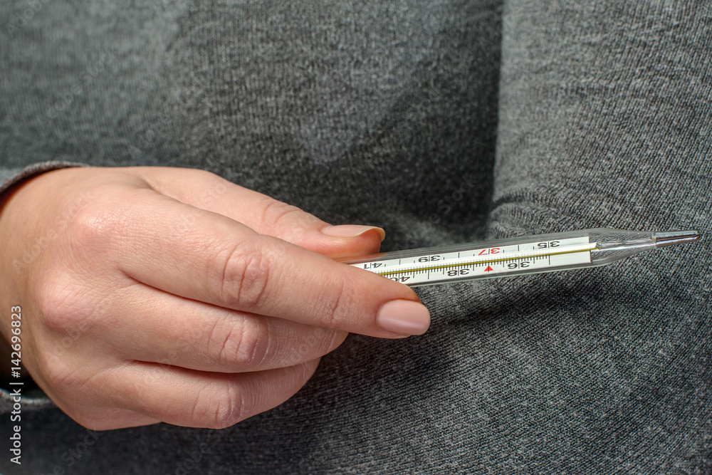 Holds the thermometer. Close-up of thermometer in woman's hand ...