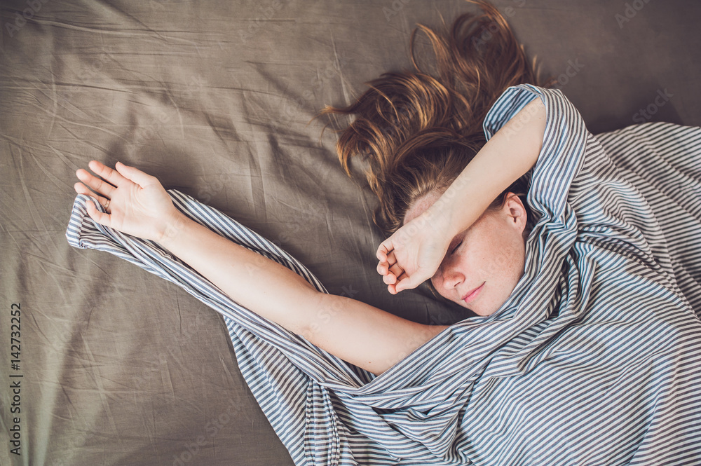 Beautiful young woman lying down in bed and sleeping, top view. Do not ...