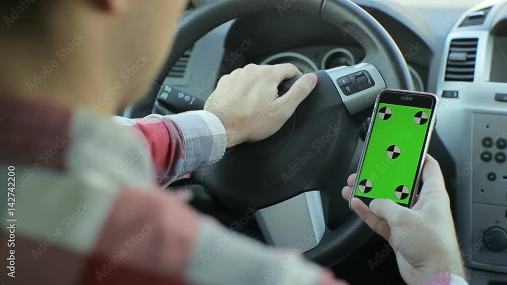 Man sits in the modern car and works on smartphone - green screen ...