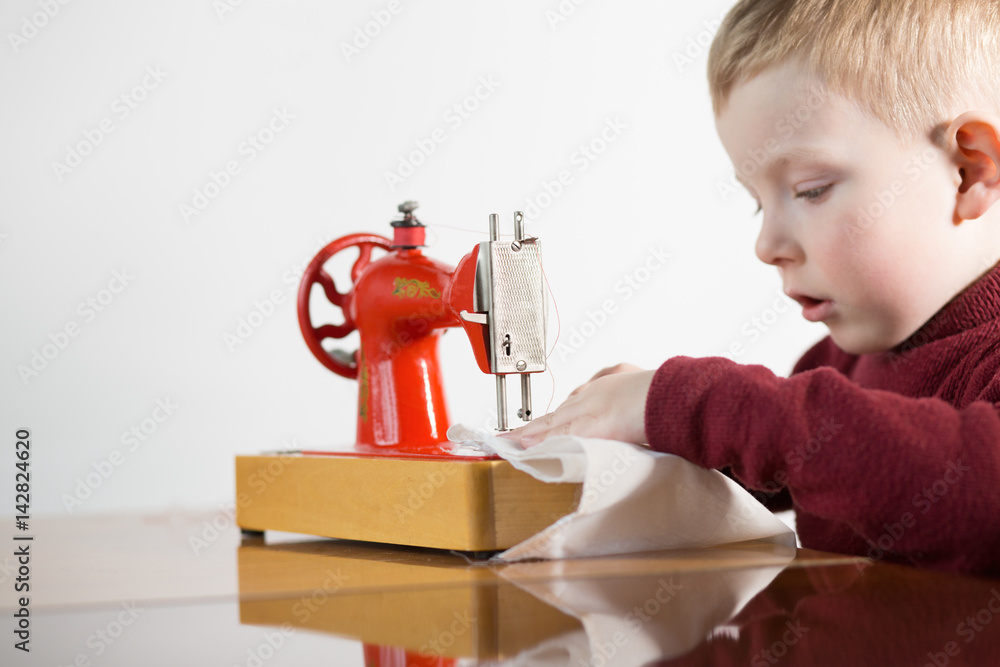 Little boy sew the fabric on the sewing machine - white background ...