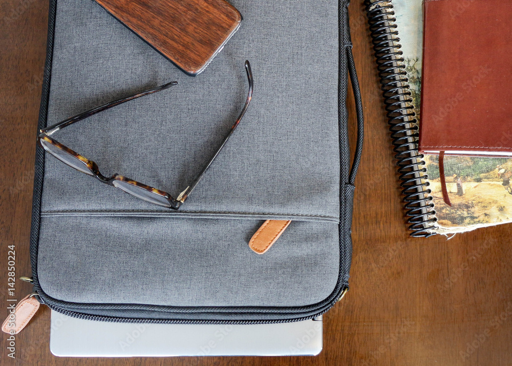 grey laptop case sits on brown table next to old book and notepad and ...