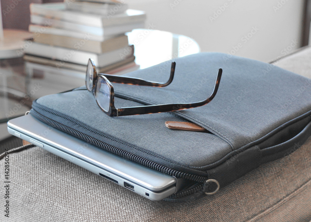 grey laptop case sits on brown table next to old book and notepad and ...