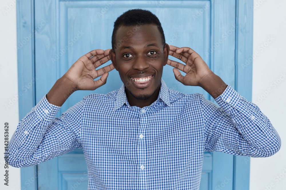 Headshot of bug-eyed young African man grimacing, looking at camera ...