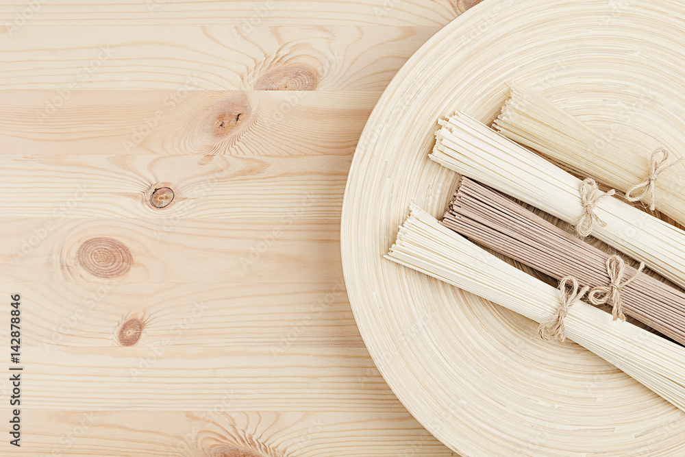 Raw asian noodles on beige wooden dish on white board, top view ...