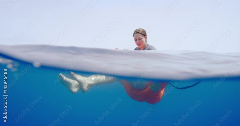 Woman floating in ocean waves wearing orange life jacket underwater ...