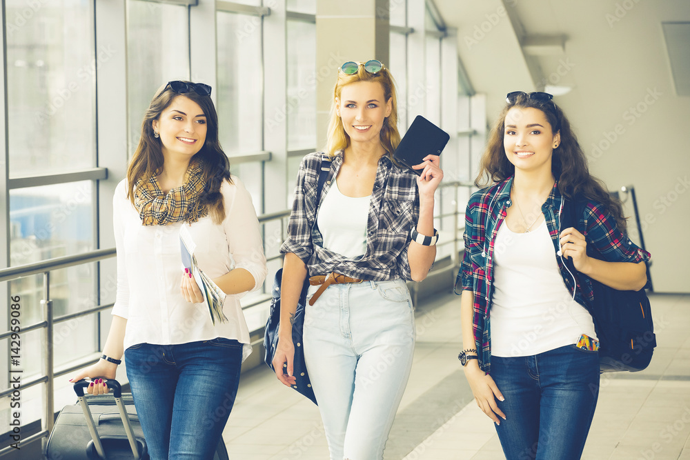 three young girls go with their luggage at the airport and laugh. A ...
