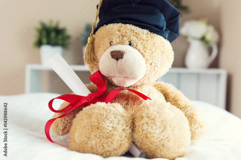 Teddy bear in graduation cap holding his diploma Stock Photo | Adobe Stock