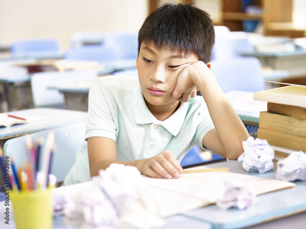frustrated asian school boy sitting alone in classroom Stock Photo ...