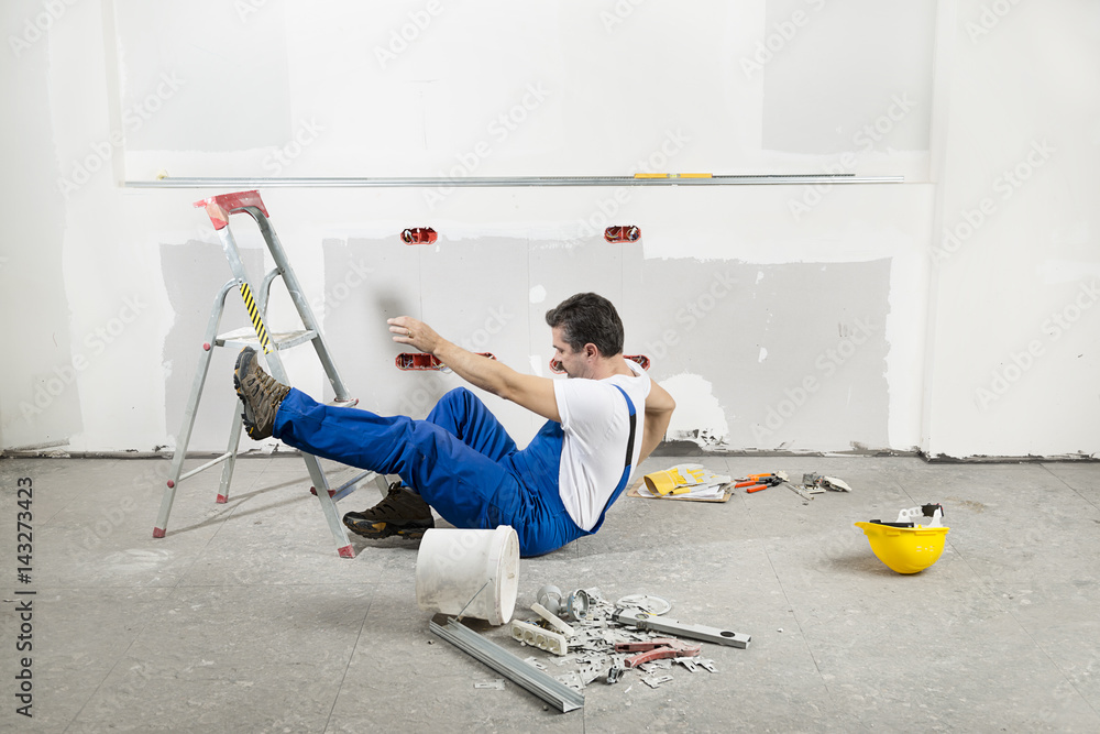 Construction worker wearing overalls falling out of ladder at ...