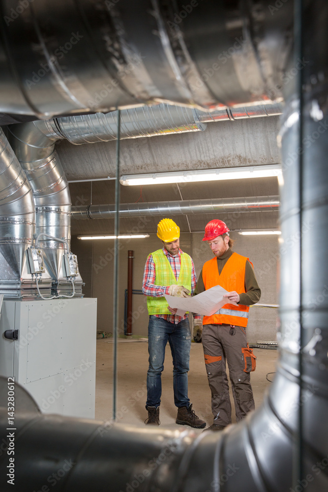 Workers making final touches to HVAC system. HVAC system stands for ...