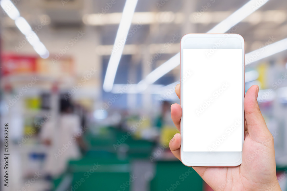 Woman hand holding mobile phone at supermarket checkout background ...