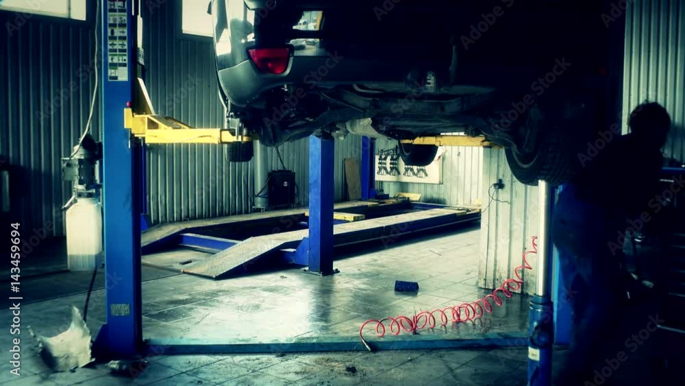 mechanic push red tools box under lifted car. Stock Video | Adobe Stock