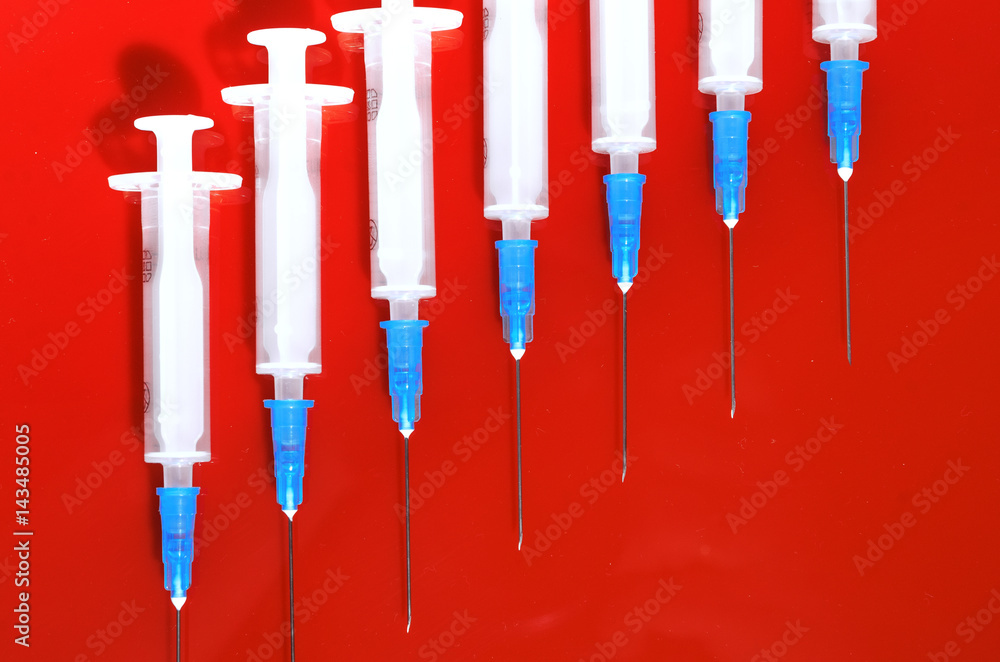 Hypodermic syringe. Syringes with blue needles on a red background ...