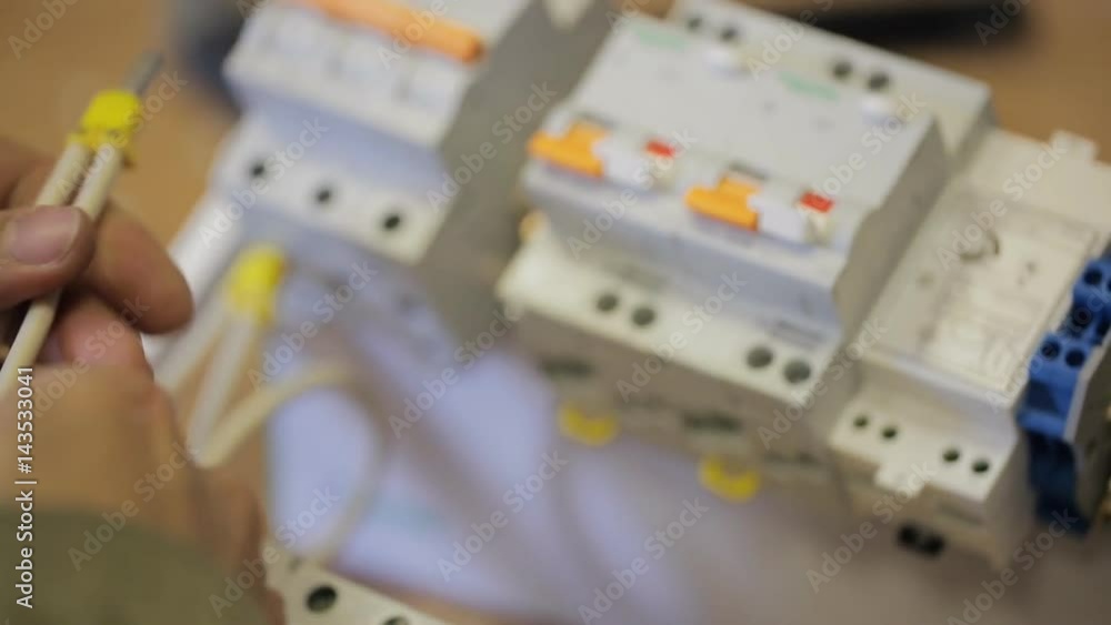 Electrician installs letters to denote different wires in switchboard ...