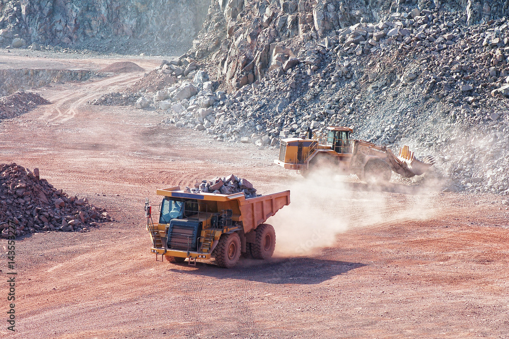 bulldozer loading dumper truck with porphyry rock material in a quarry ...