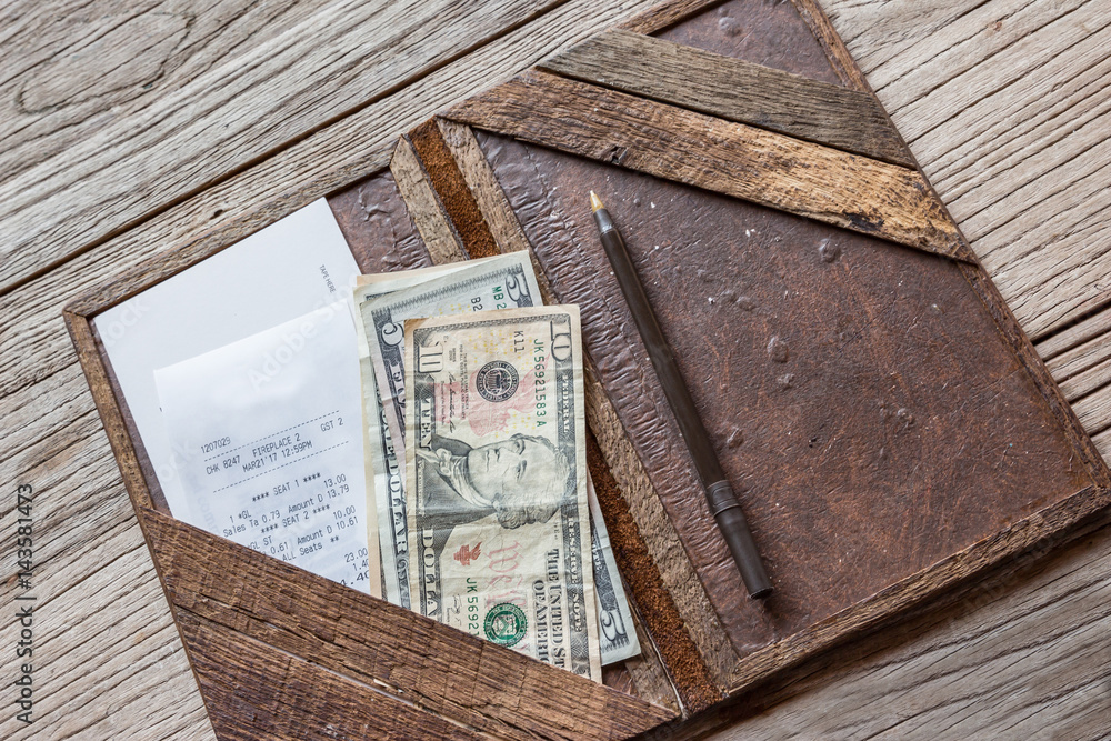 horizontal image of a brown leather bill folder with a drink bill and ...