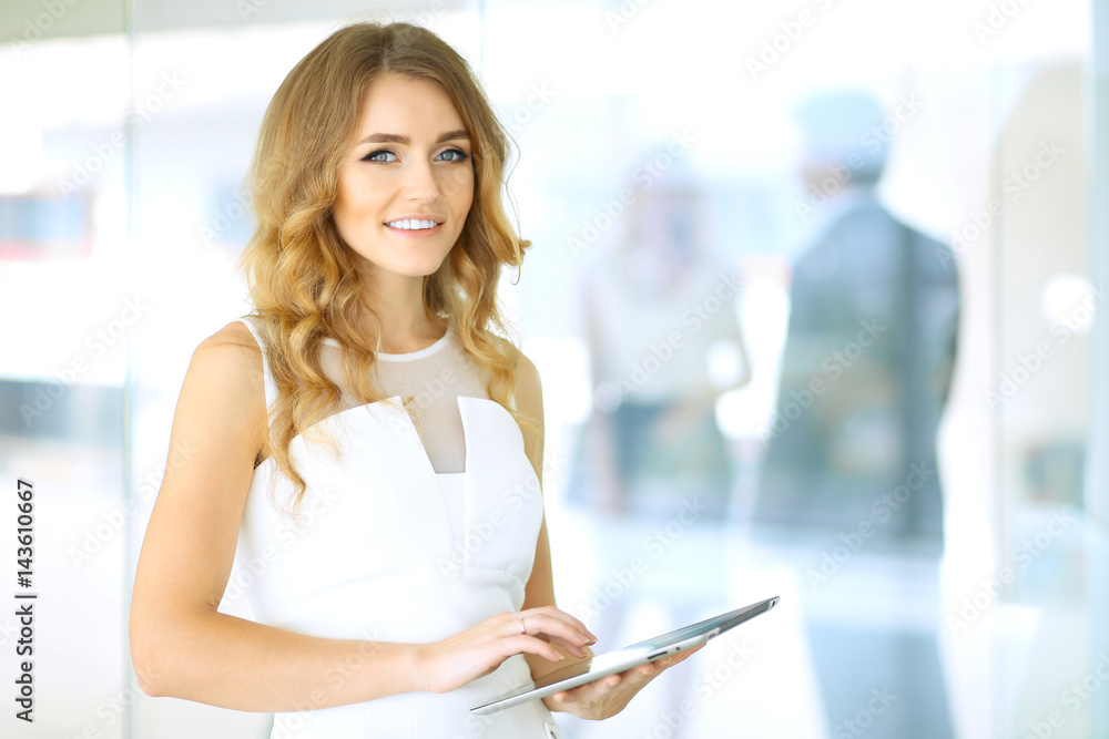 Blonde woman with touchpad computer looking at camera and smiling while ...