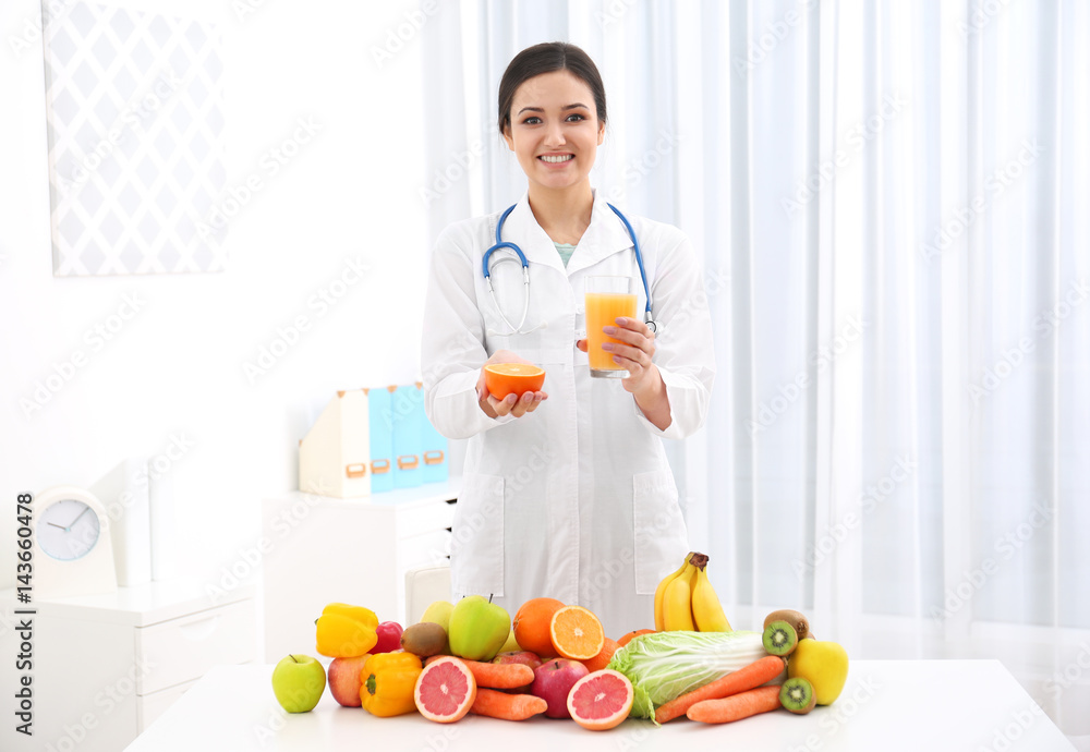 Female nutritionist with different fruits and vegetables at desk Stock ...