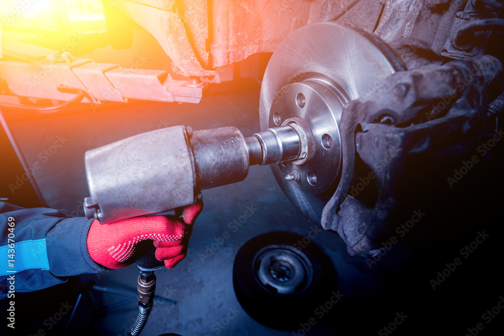 Professional car mechanic working with pneumatic wrench in auto repair ...