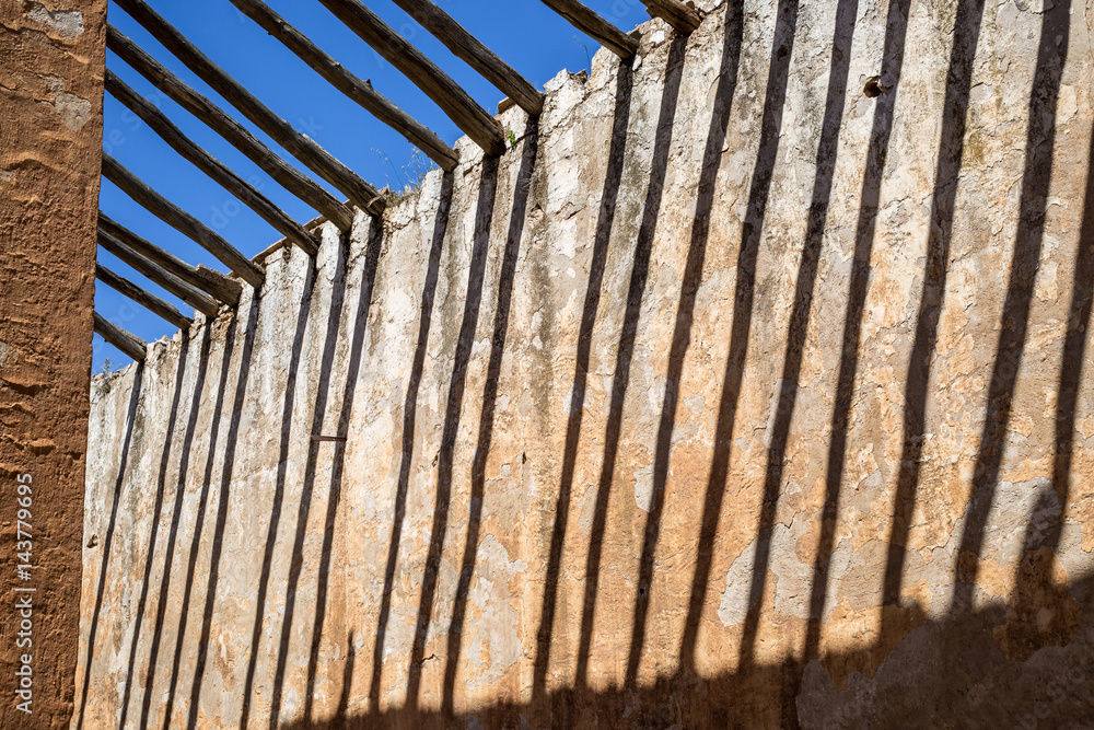 Wooden beams of roofless ancient building cast shadows over chipped and ...