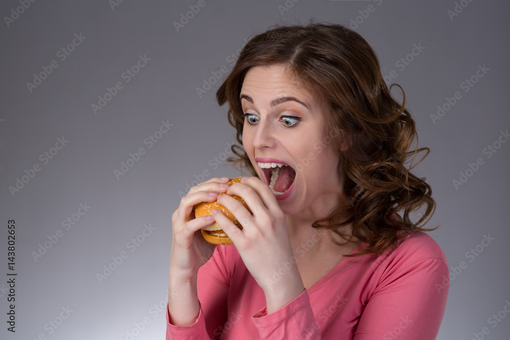 young beautiful girl disdainfully holding a junk food from fast food ...