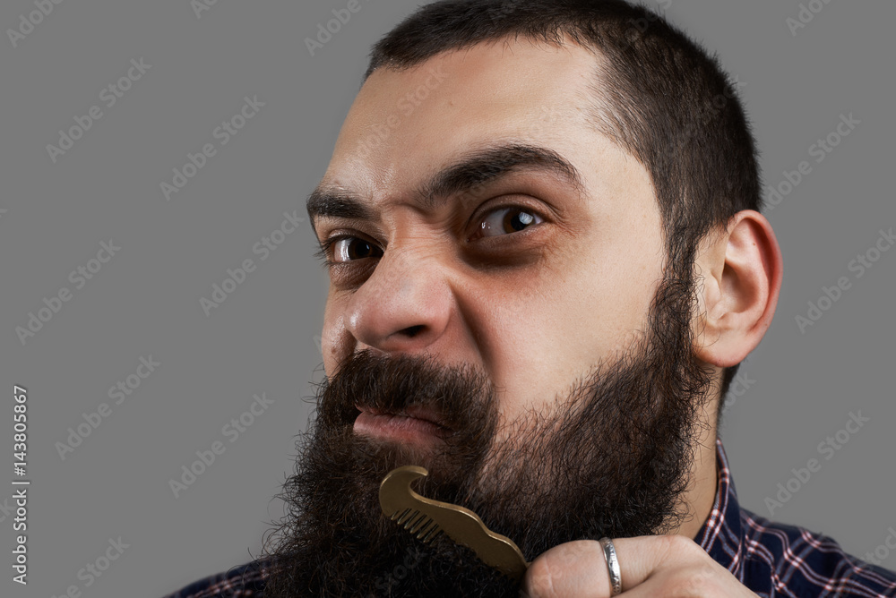 Funny face of brutal man who comb his big beard. Crazy emotion on male ...