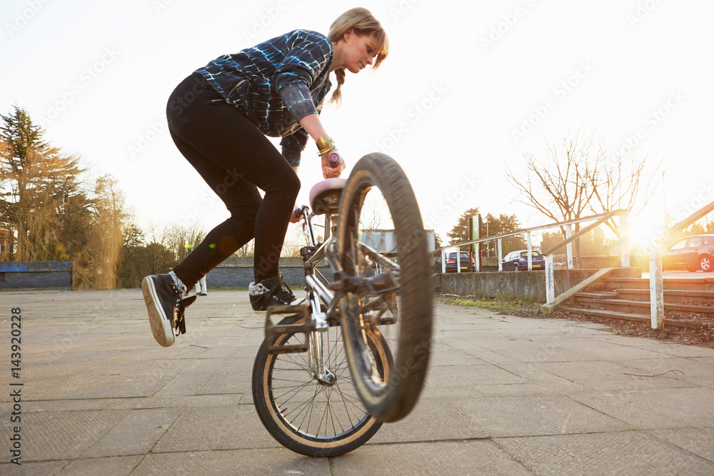 Female BMX rider doing BMX trick in park Stock Photo | Adobe Stock