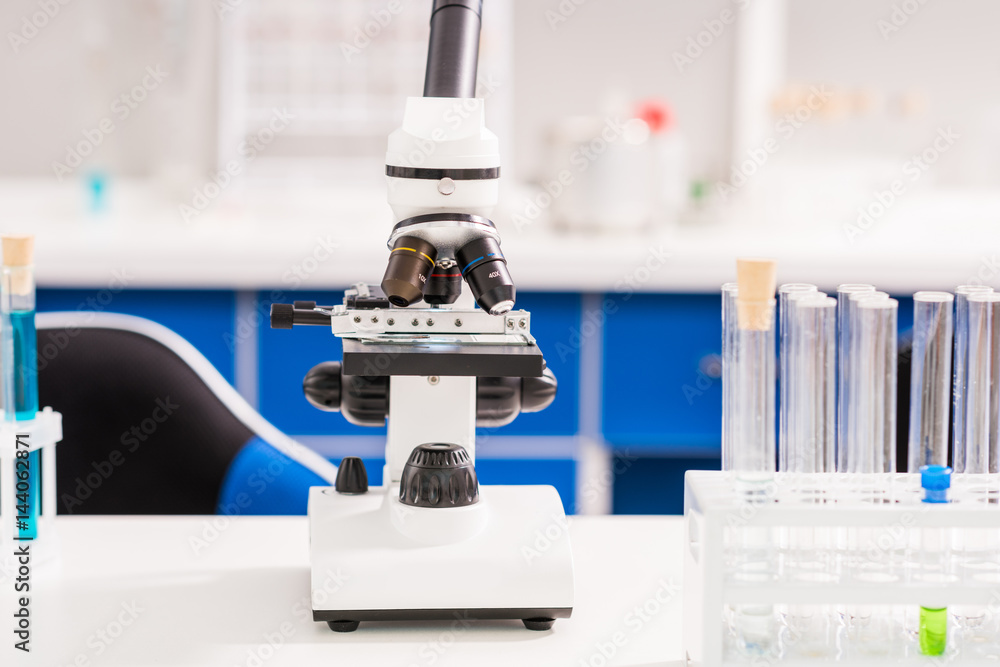 tubes and microscope standing on table in empty chemical laboratory ...