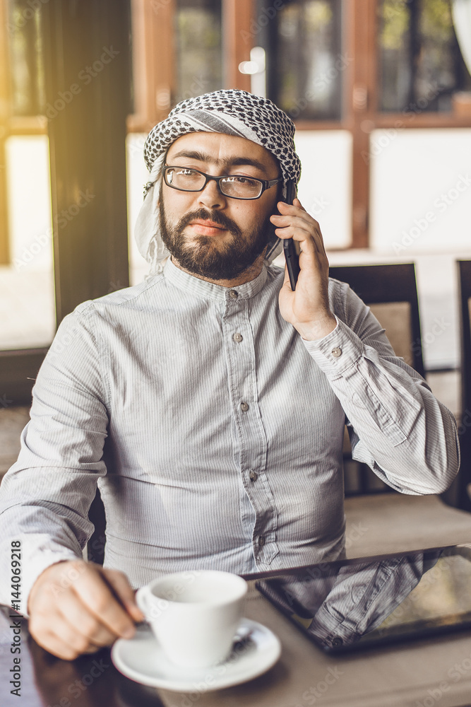 Arab man is drinking coffee in a cafe. Stock Photo | Adobe Stock