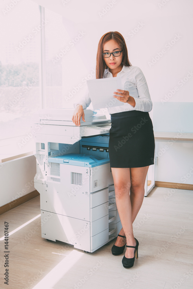Asian Business Woman Reading Document at Copier foto de Stock | Adobe Stock