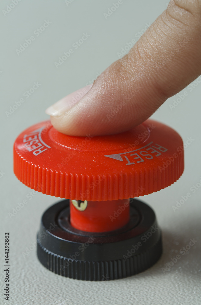 Finger touch on red emergency stop switch button on control panel for ...