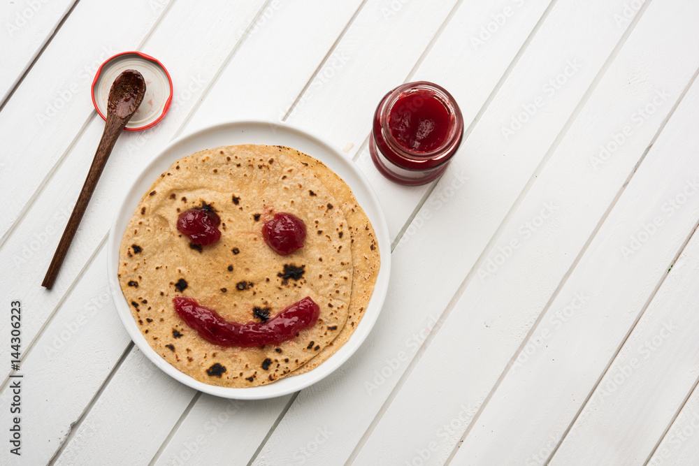 ketchup or fruit jelly/jam smile emoticon over indian bread / chapati ...