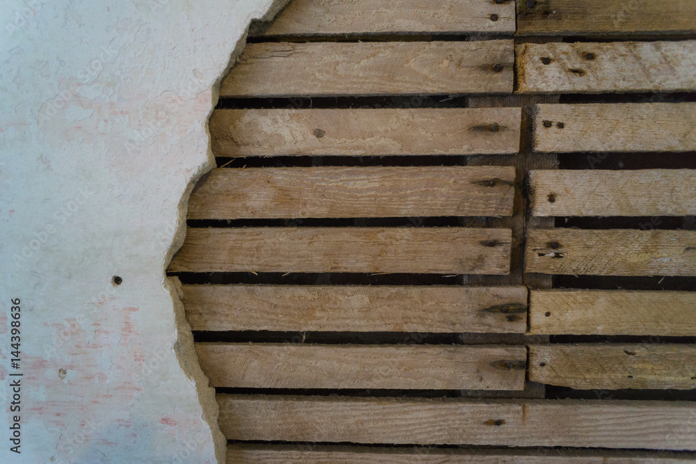 Damaged wall with broken drywall and exposed slats and timber ...