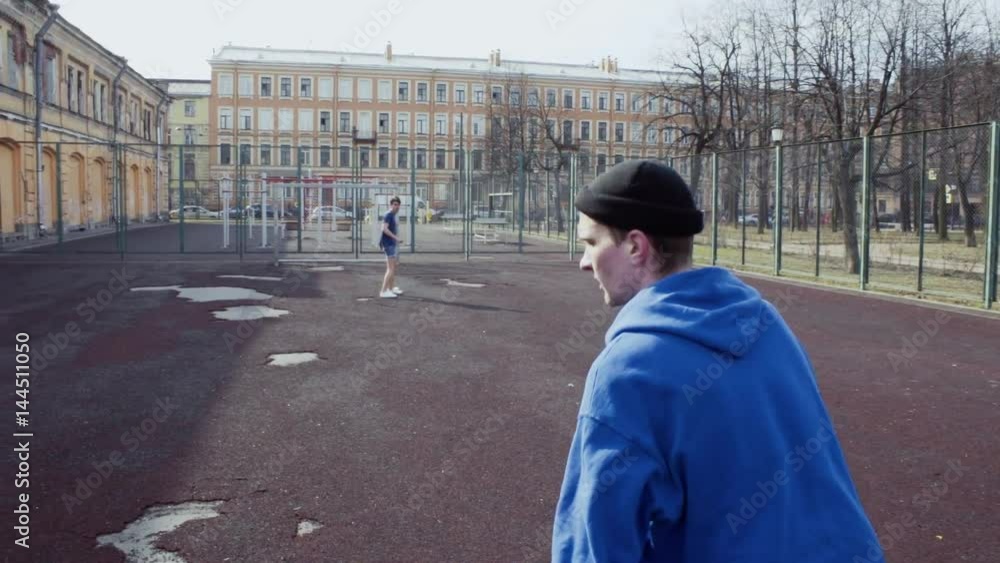 Two young men playing football at city park. Soccer players kicking the ...