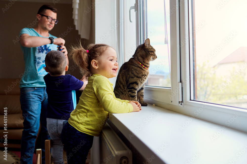 A happy family. Little girl looks out the window on background of her ...
