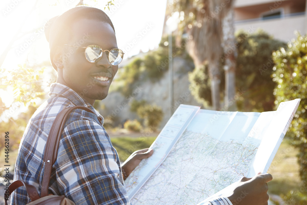 Attractive stylish Afro American tourist looking at camera with happy ...