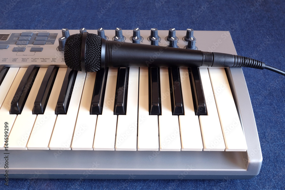 Black microphone on electronic synthesizer keyboard with many control ...