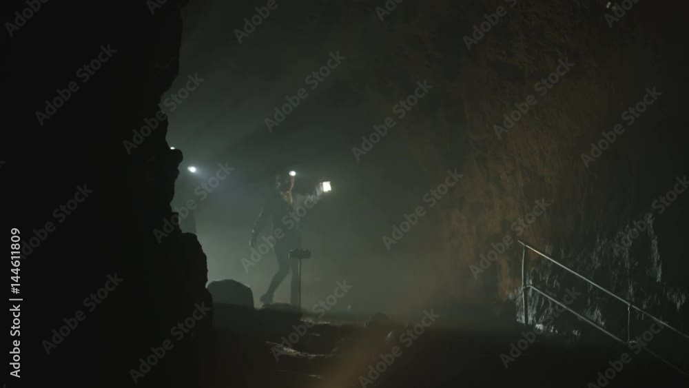 Team of geologists exploring underground cave, looking at rock ...