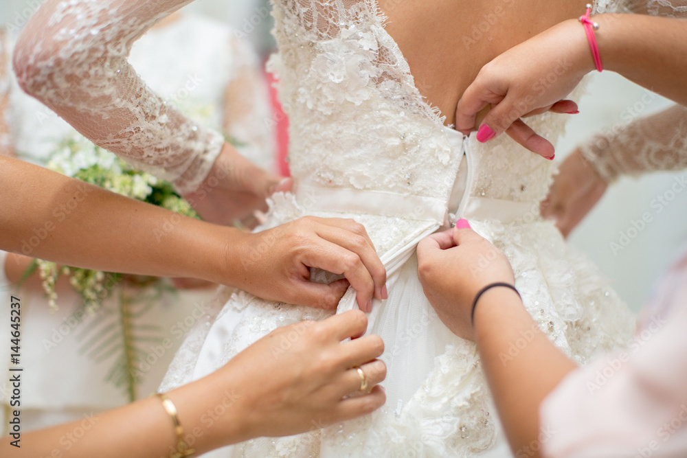 Bridesmaid hands helping the bride to dress for the wedding ceremony ...