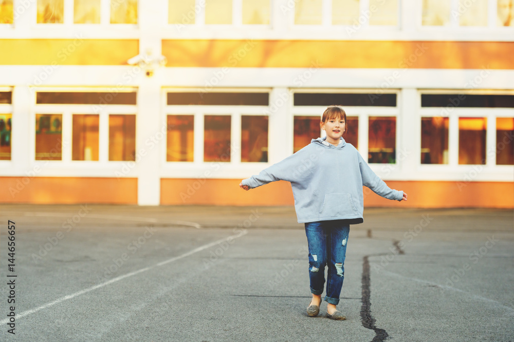 Cute 9 year old kid girl playing on school yard, wearing denim jeans ...