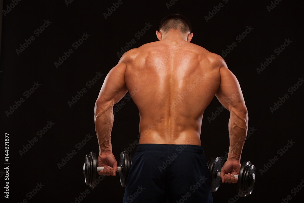 Muscular male model bodybuilder doing exercises with dumbbells, turned ...