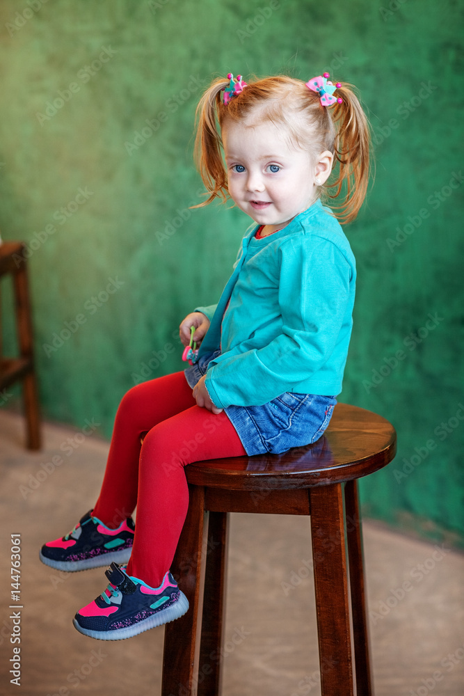 The little girl in shorts sitting on a chair. The concept of childhood ...