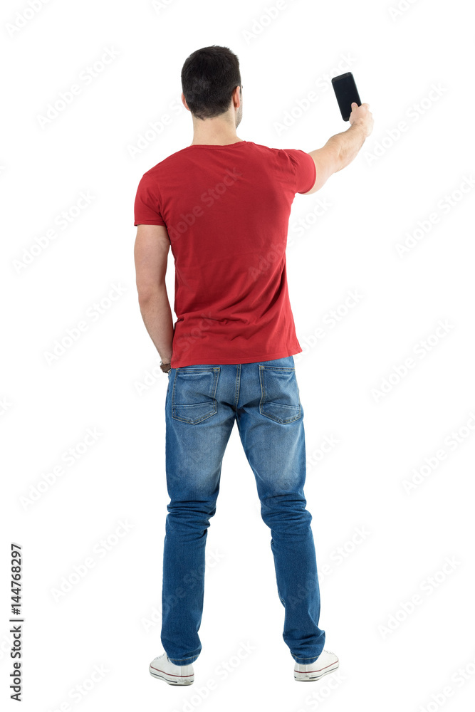 Backside view of young casual man taking photo with mobile phone. Full ...