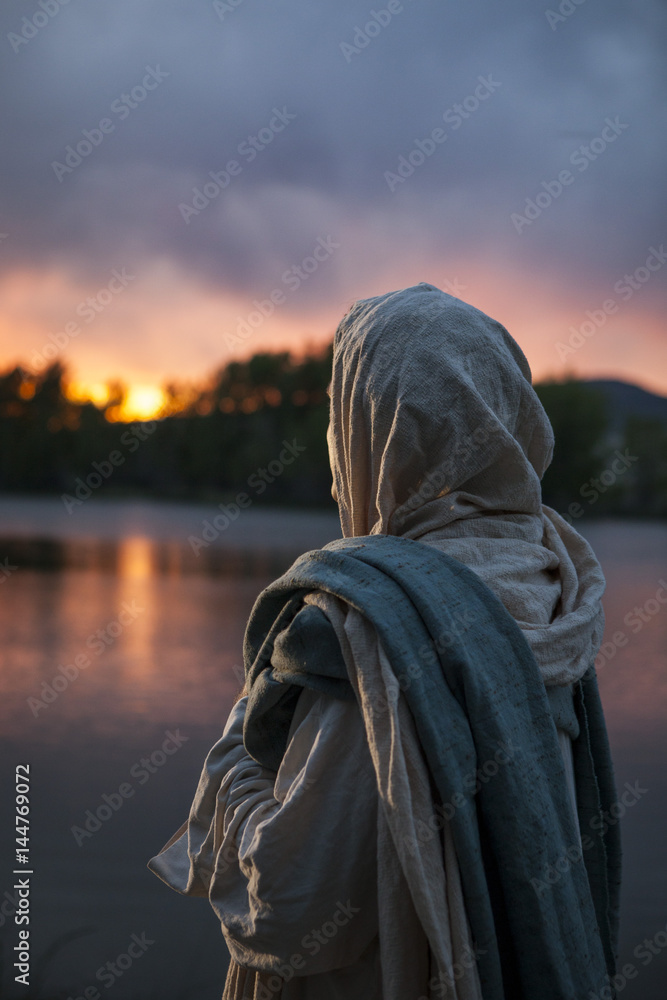 Jesus Christ looking over a lake during a sunset Stock Photo | Adobe Stock