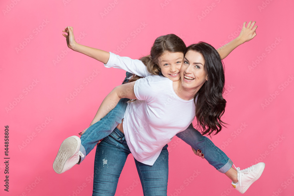 Happy mother piggybacking adorable little daughter smiling at camera foto de Stock | Adobe Stock