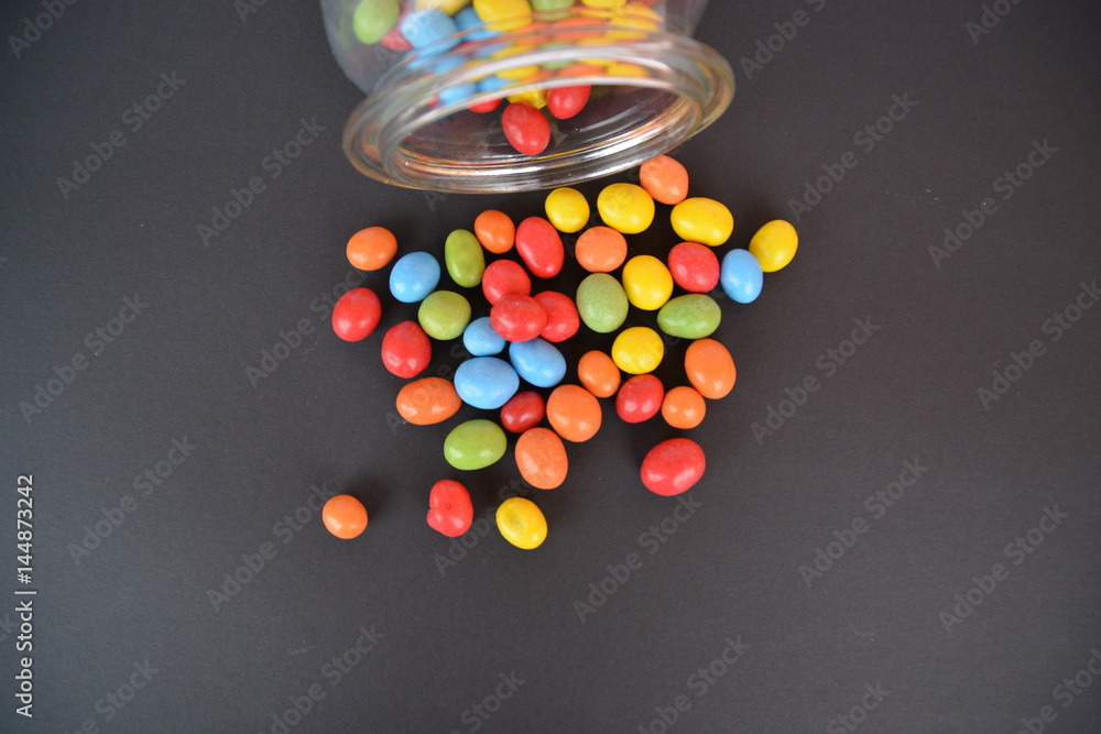 chocolate lentils in a jar on a black ground with colored background ...
